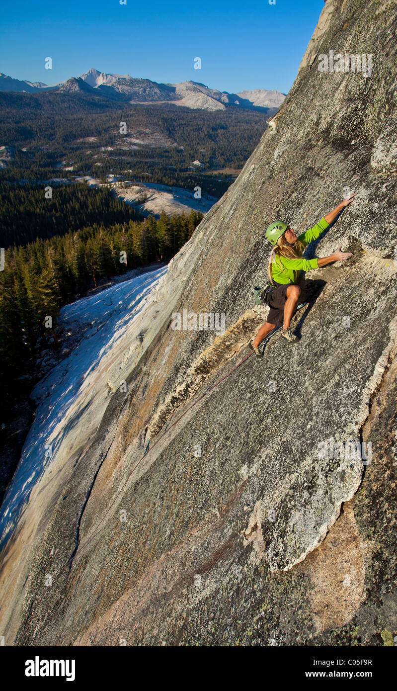 Female rock climber struggles for her next grip on the edge of a steep ...