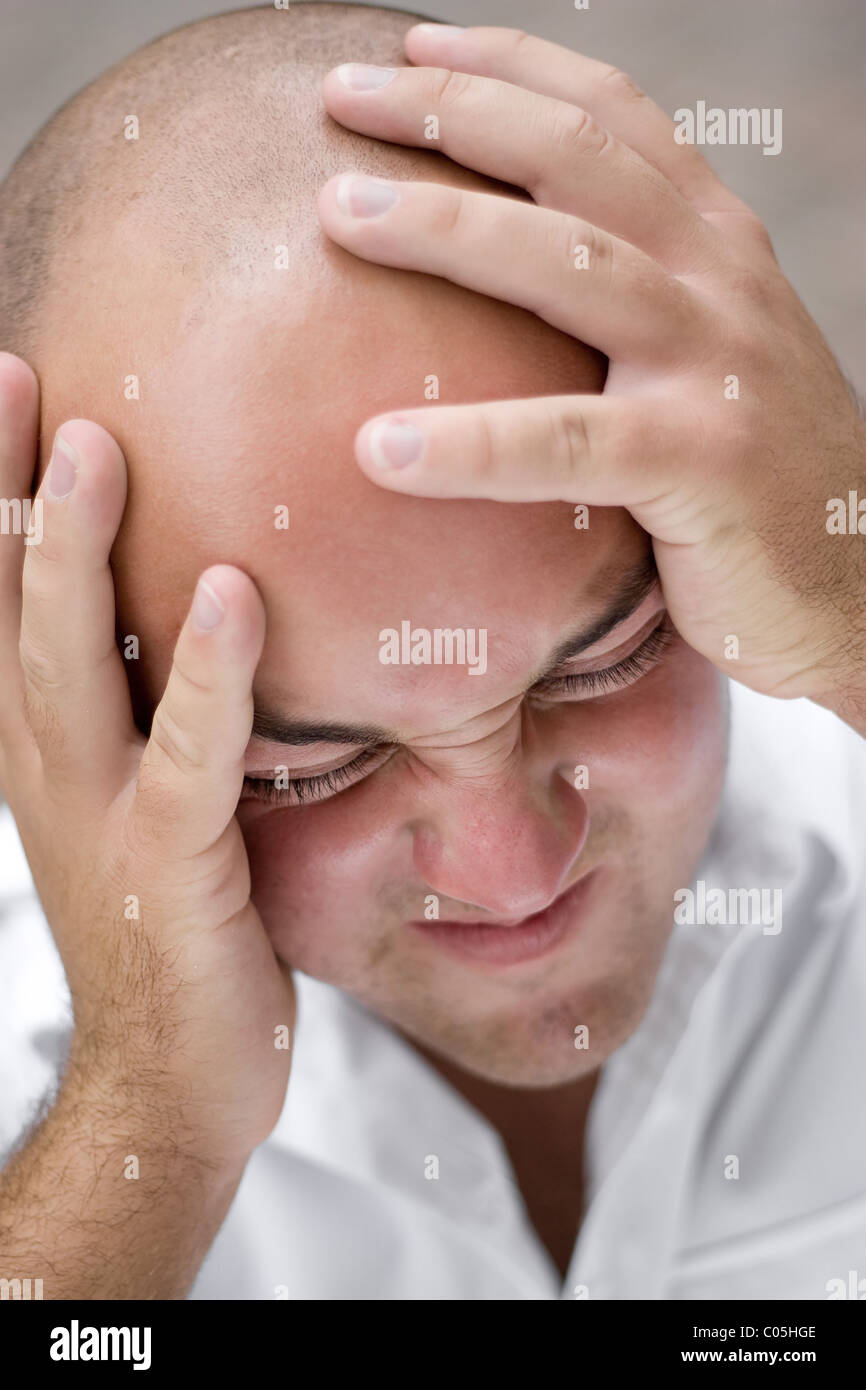 A young man that looks to be upset and grabbing his head in pain or ...