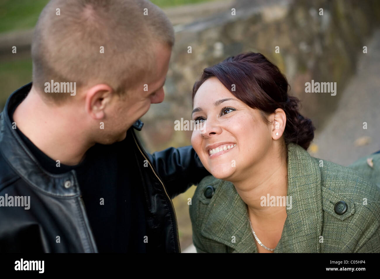 A young happy couple looking fondly at one another outdoors. Shallow ...