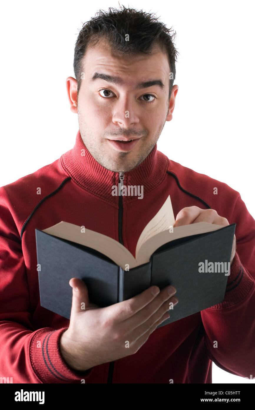 A young man reading a book with a surprised expression on his face ...