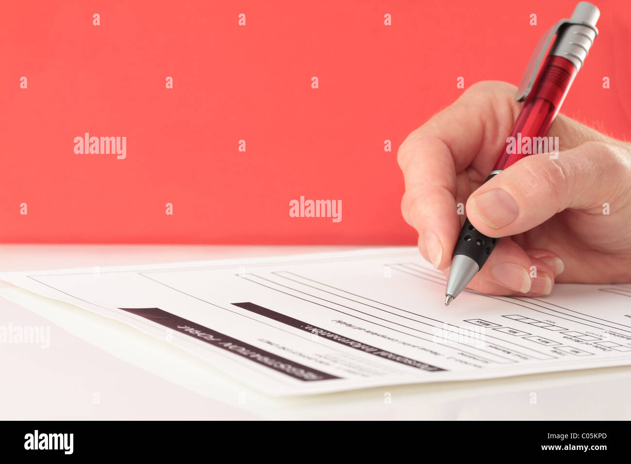 Red Themed Pen in Hand Completing Form Stock Photo - Alamy