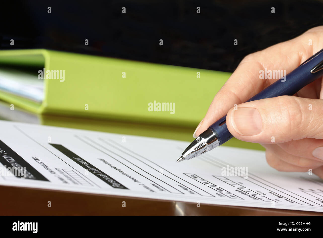 Hand with Pen Signing Form by Green Folder Stock Photo - Alamy