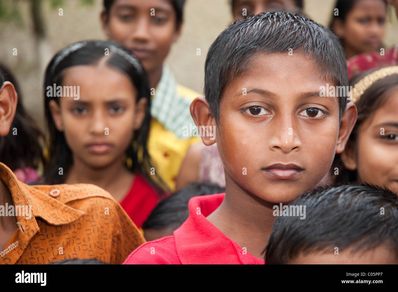 A group of Bangladeshi children with boy staring intently at the camera ...