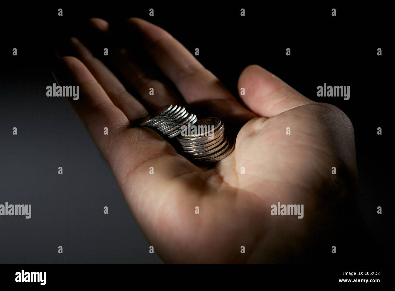 A hand and holds money in coins between the palm of the right hand with ...