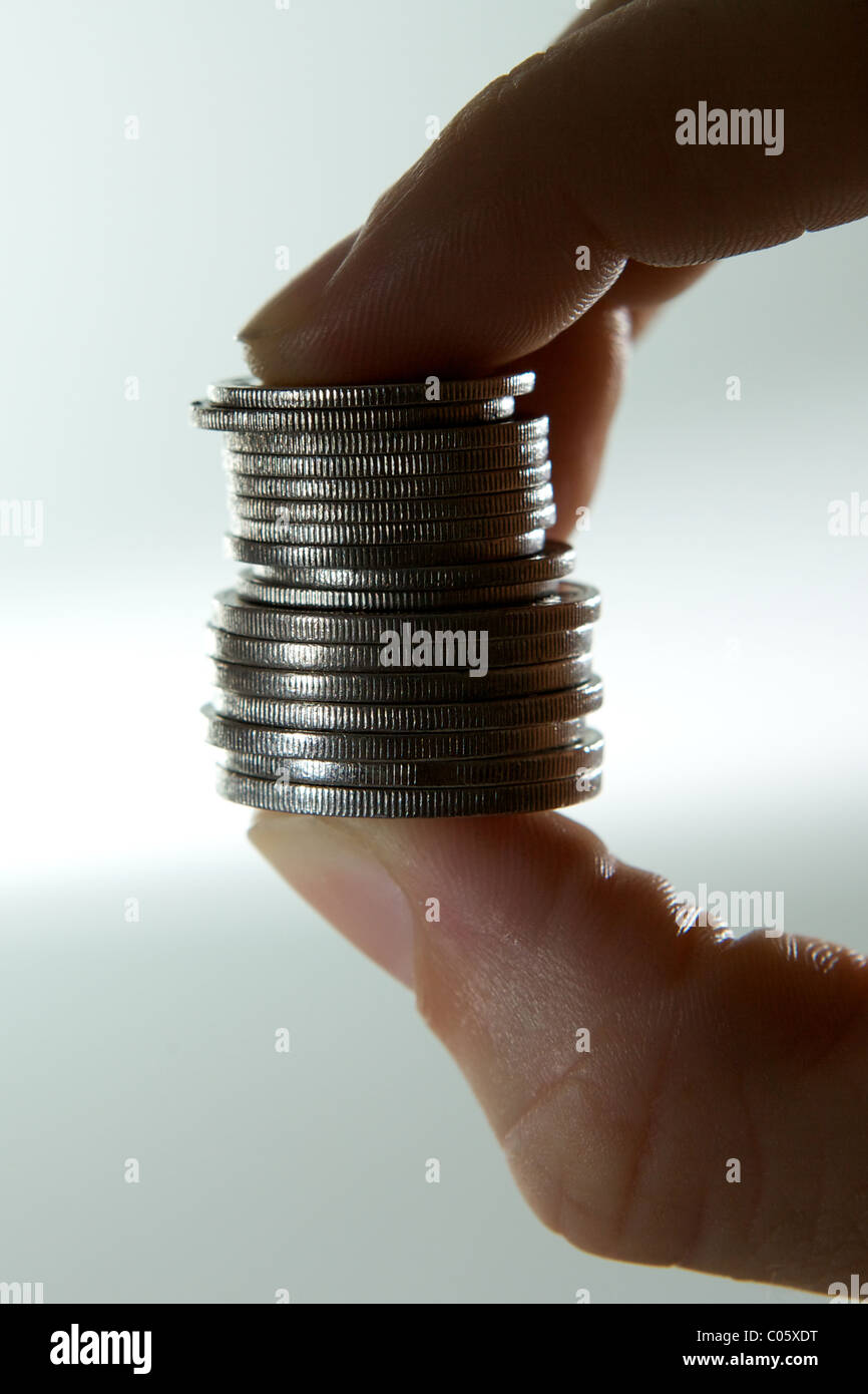 A hand holds money in coins between the finger tips with clear ...