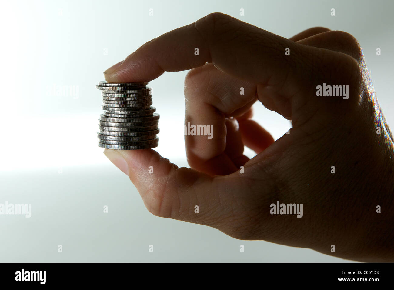 A hand and holds money in coins between the finger tips with clear ...