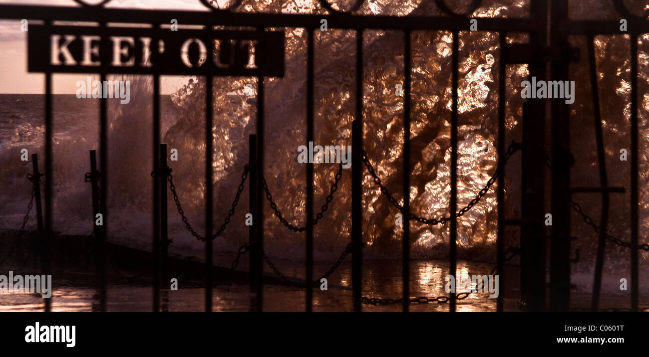 Keep Out sign on a metal gate with railings and trees in the background ...