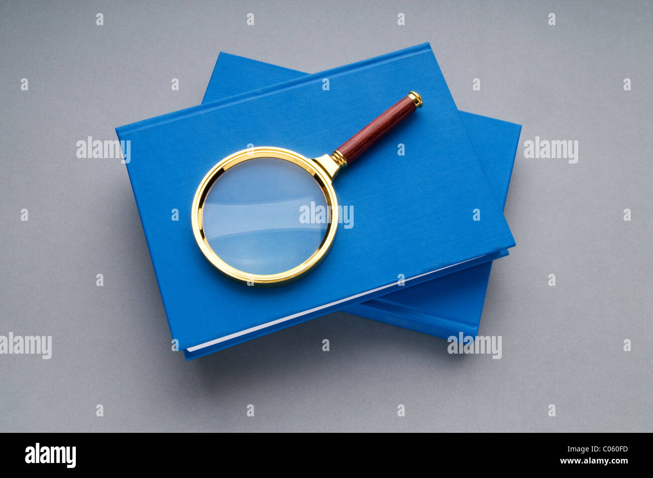 Magnifying glass over the stack of books Stock Photo - Alamy