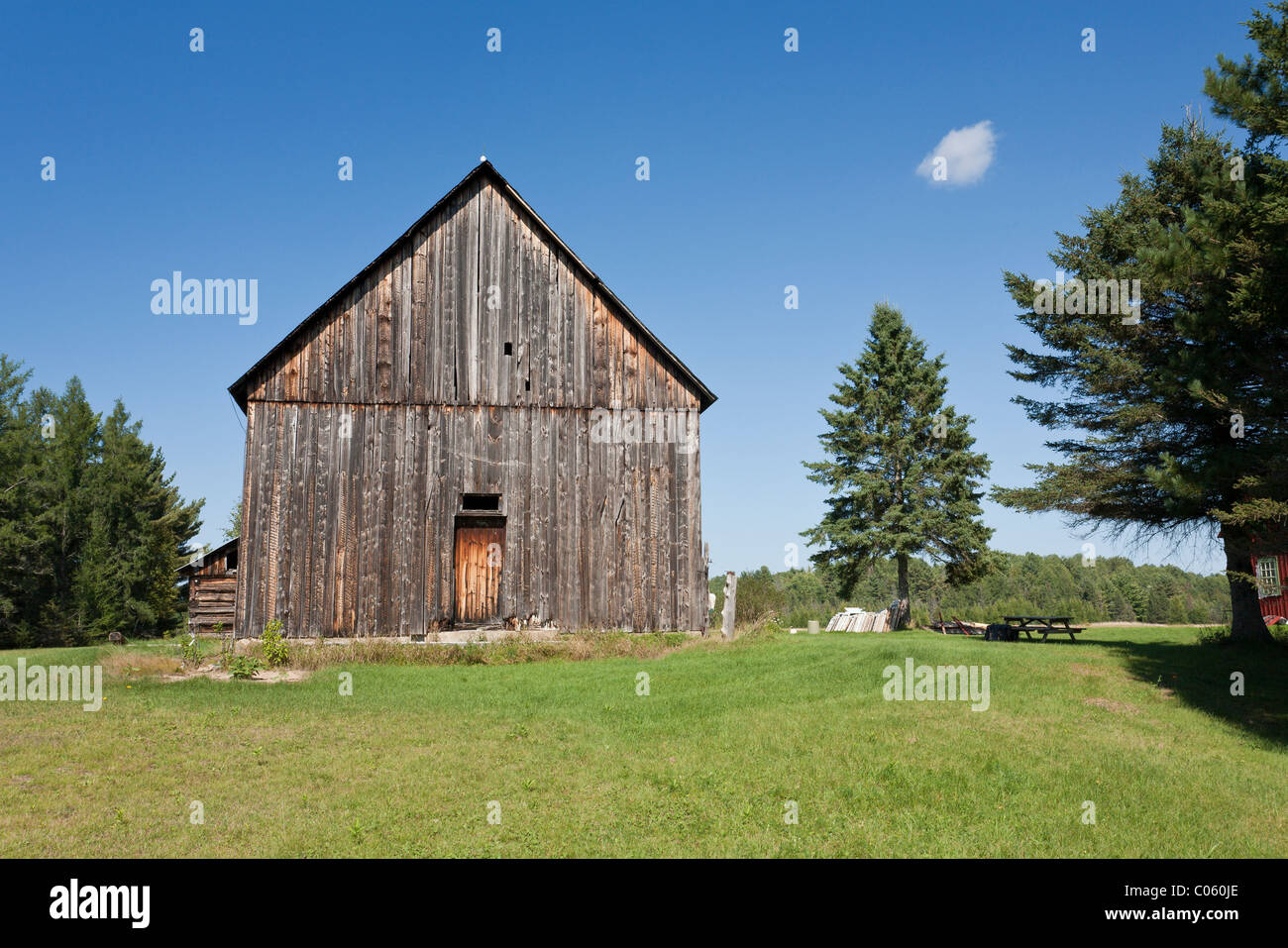 Old Quebec Farmstead. An old barn, set in a grassy yard and weathered ...