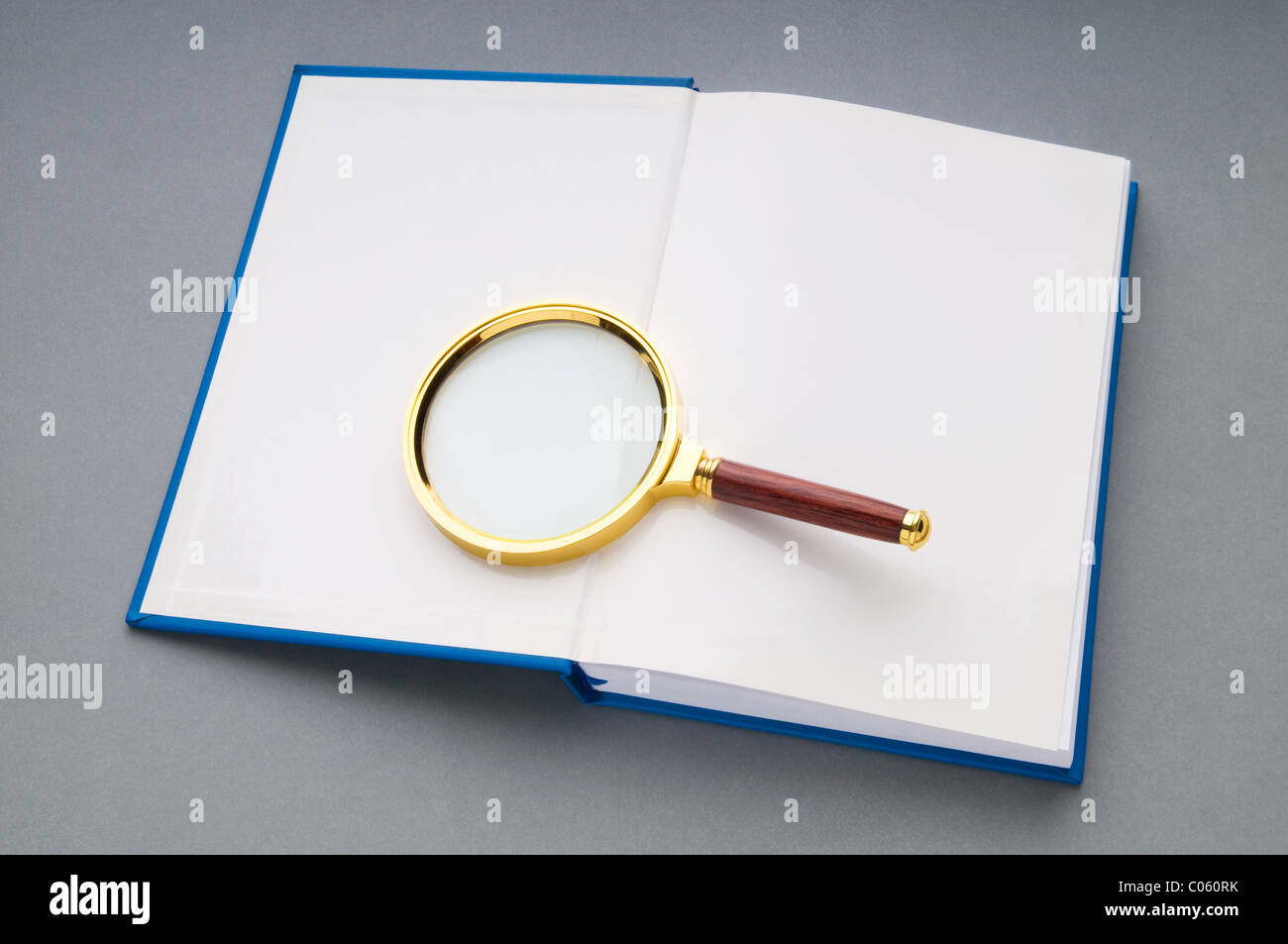 Magnifying glass over the stack of books Stock Photo - Alamy