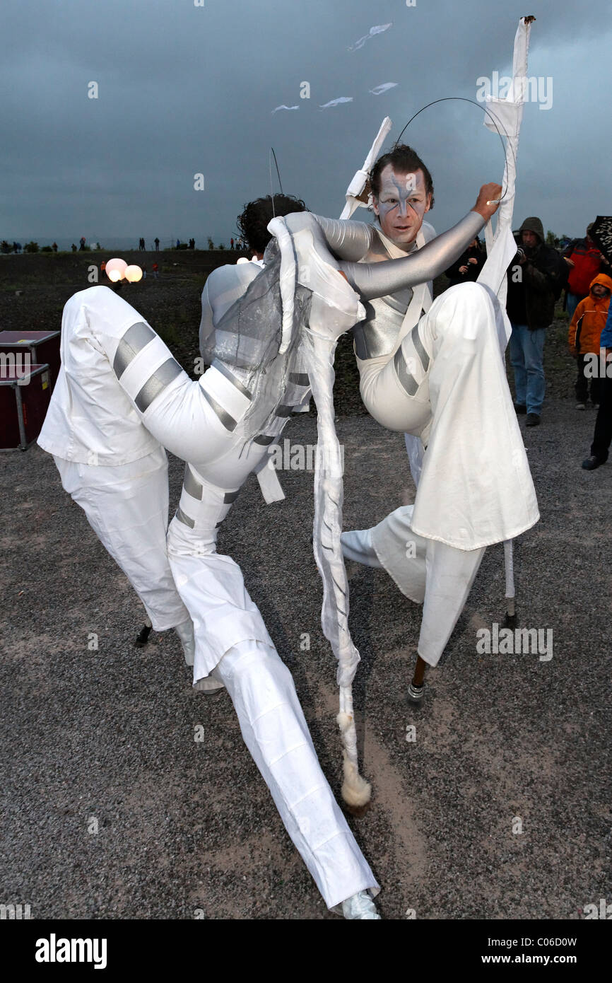 Two performers on stilts, twisted, dressed fantastically, summer night ...