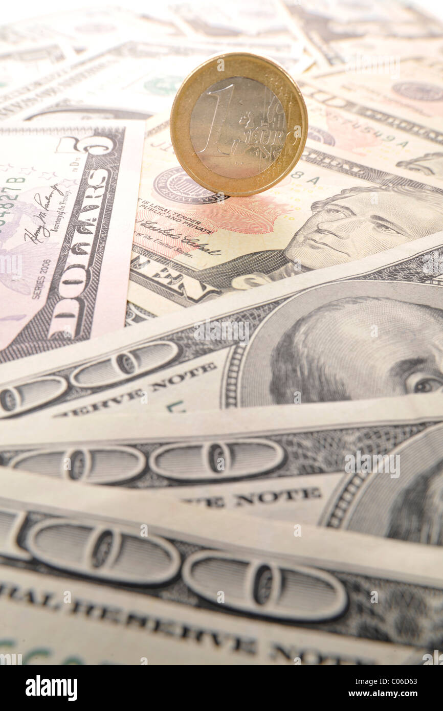 1 euro coin balancing on U.S. dollar banknotes, symbolic image of ...