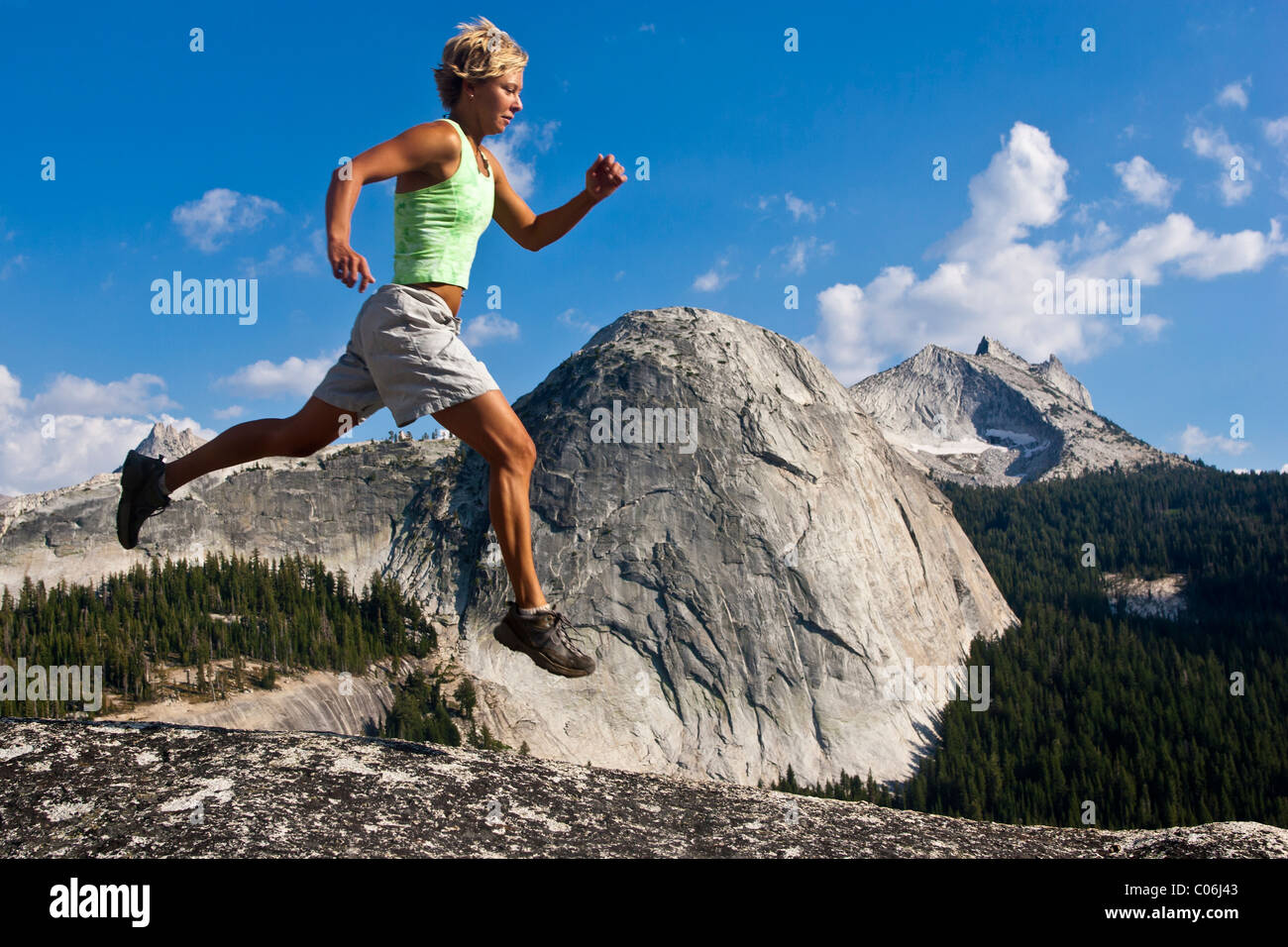 Female trail runner leaps an obstacle along a mountain top Stock Photo ...