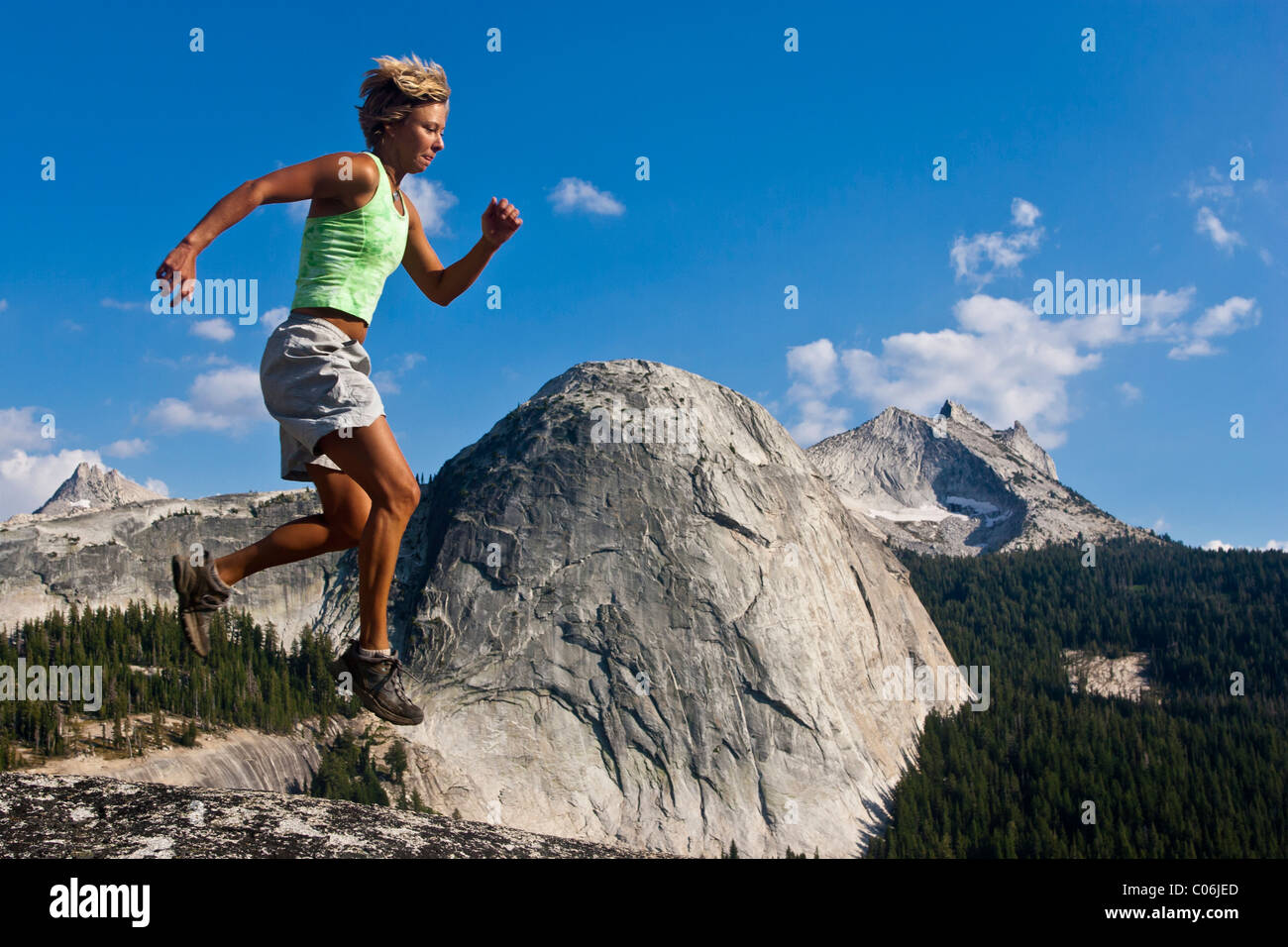Female trail runner leaps an obstacle along a mountain top Stock Photo ...