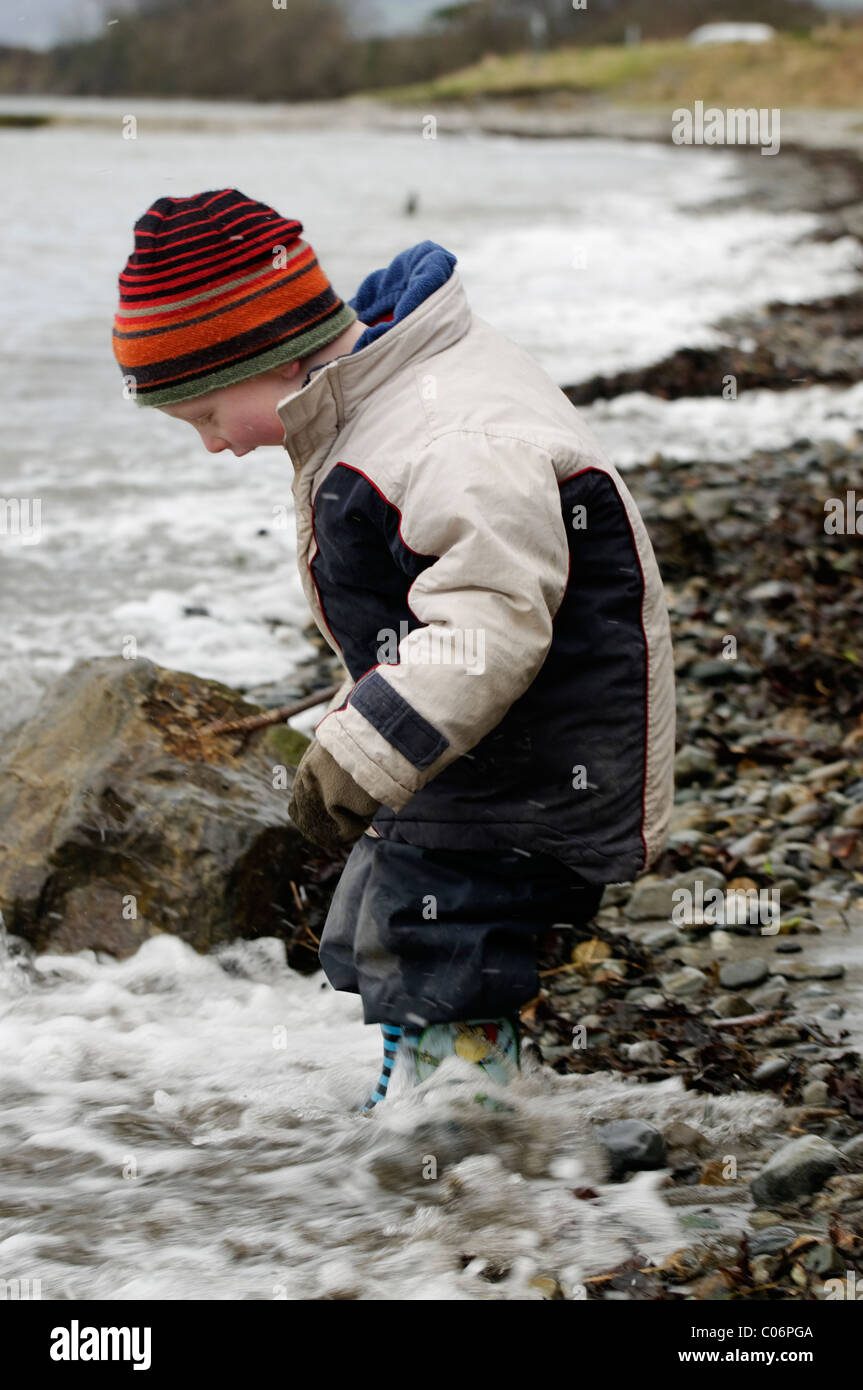 A young boy playing on the beach on a cold day Stock Photo - Alamy