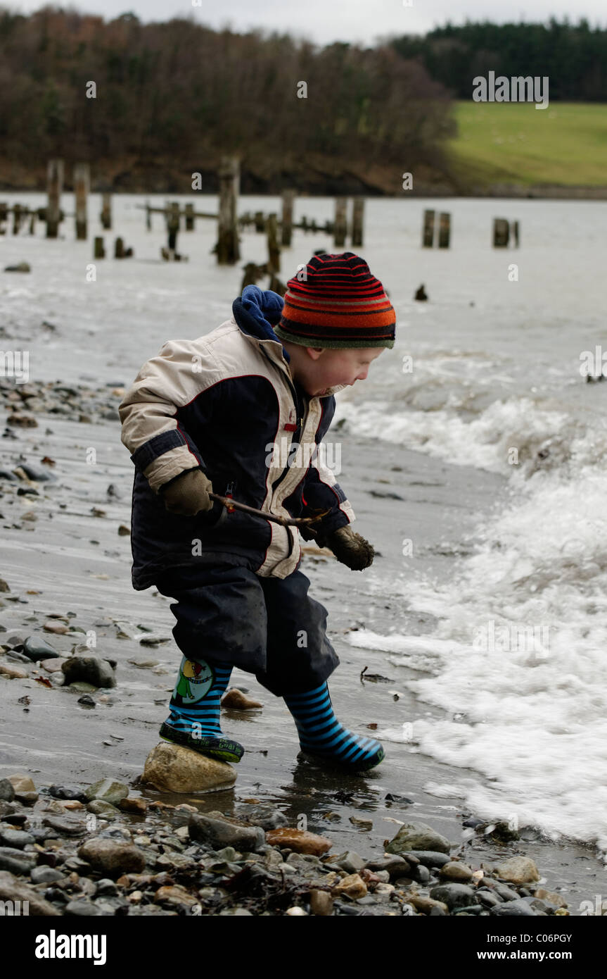 A young boy playing on the beach on a cold day Stock Photo - Alamy