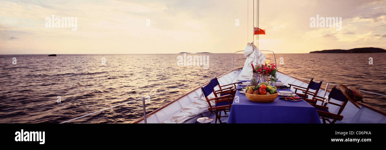 Sailing boat with set table out to sea in sunset Stock Photo - Alamy