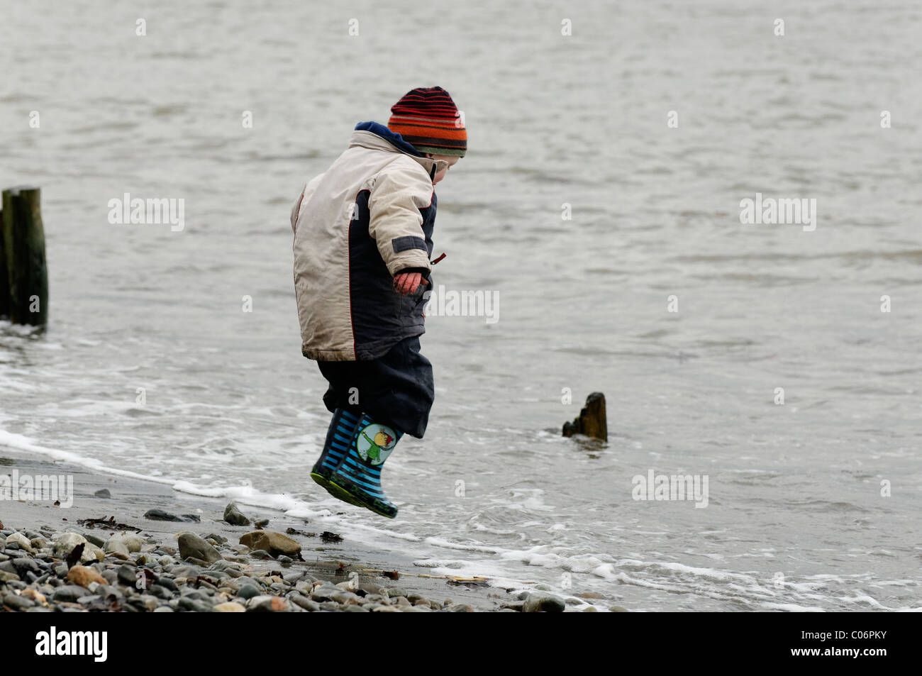 A young boy playing on the beach on a cold day Stock Photo - Alamy