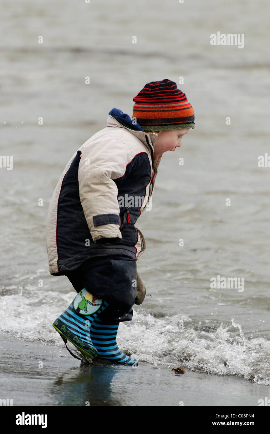 A young boy playing on the beach on a cold day Stock Photo - Alamy