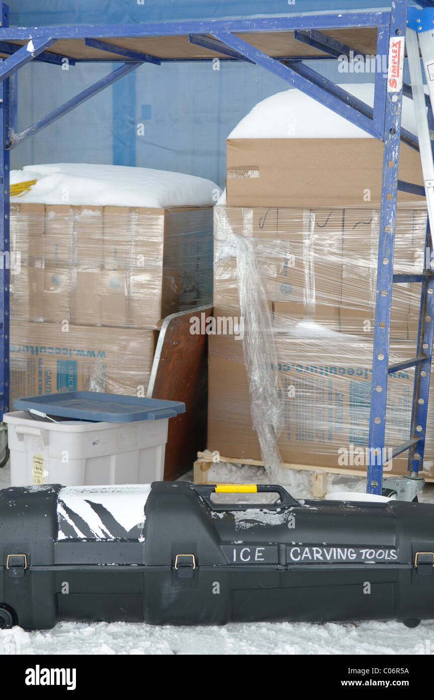 A crate of ice carving tools lays before packaged ice blocks at the ...
