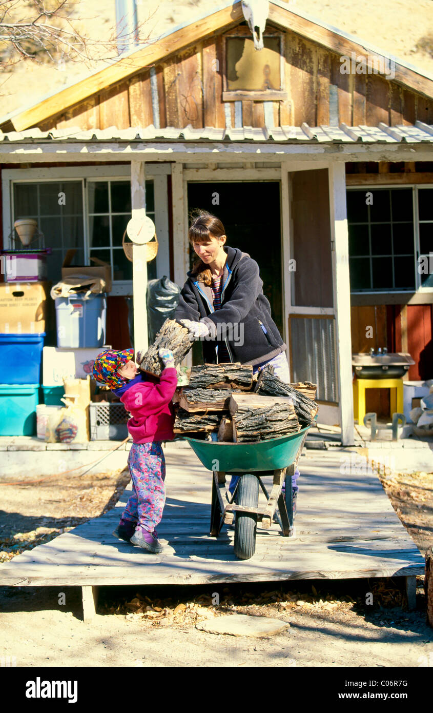 Mother and daughter carry firewood in a wheelbarrow Stock Photo - Alamy