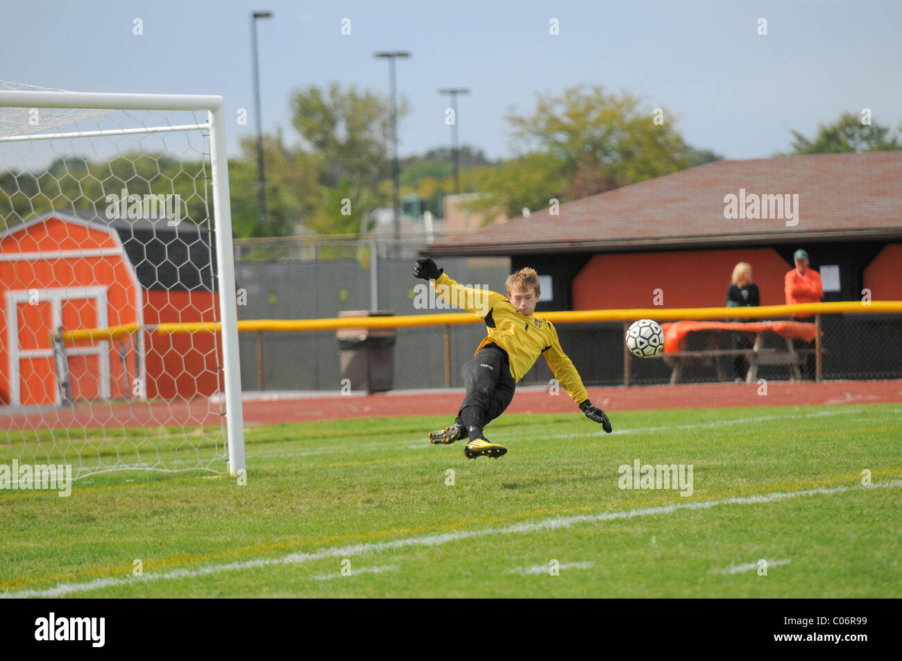 High school goal keeper makes a diving kick safe on shot during a shoot ...