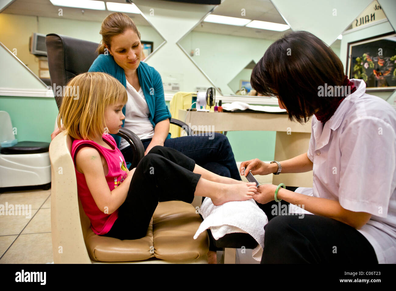 Mom watches her four year old daughter have a pedicure from a ...