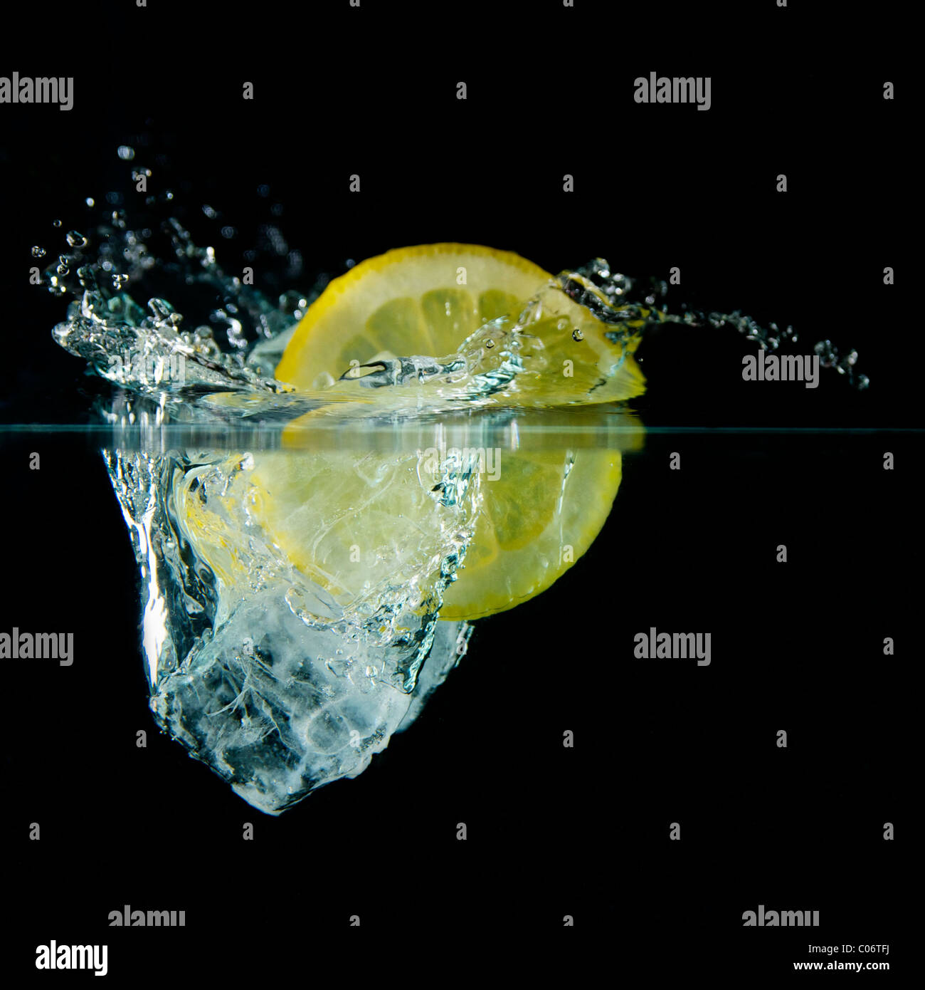 Slice of lemon and ice dropped into water Stock Photo - Alamy