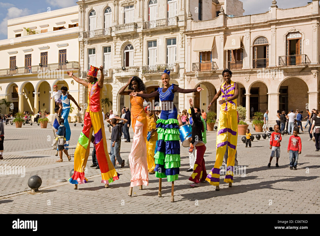 A group of street artist or performers parading on stilts walk through ...