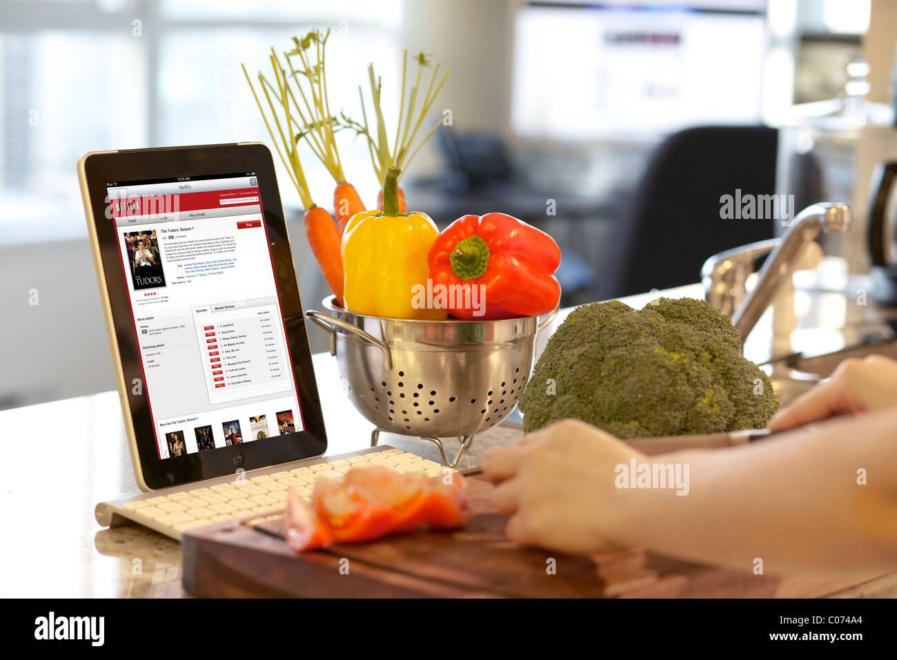 Busy woman cooking in the kitchen while browsing movies on Netflix from ...