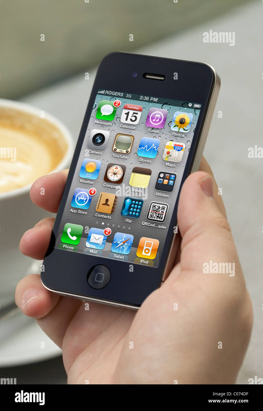 Man hand holding an iPhone 4 showing the application screen at a cafe ...