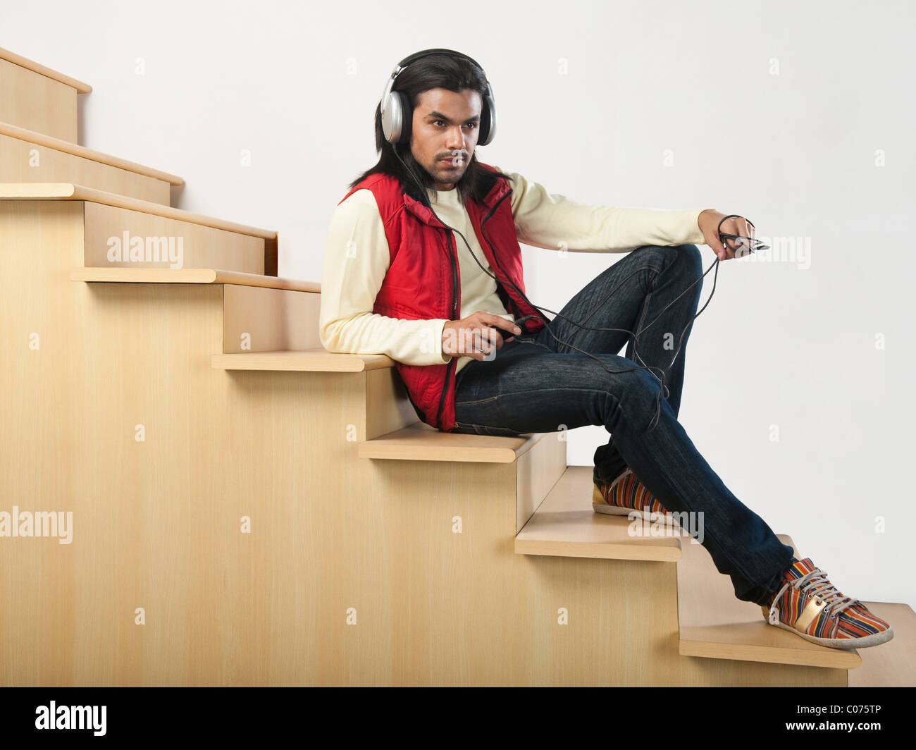Man listening to an MP3 player on a staircase Stock Photo - Alamy