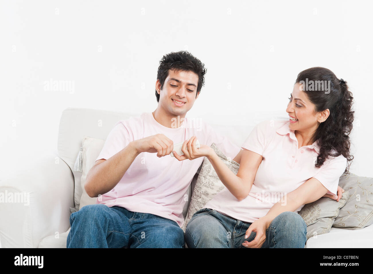 Couple playing with a remote control on a couch Stock Photo - Alamy