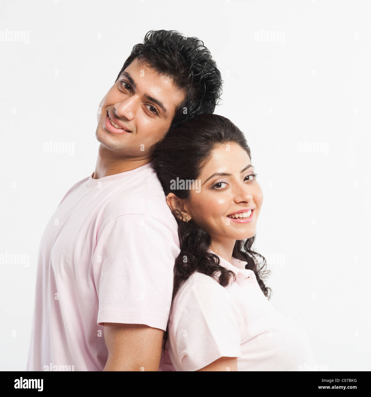 Couple standing back to back and smiling Stock Photo - Alamy
