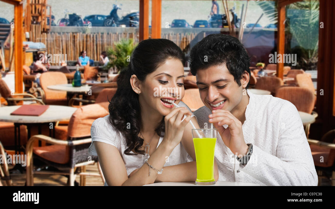 Couple sharing a glass of juice in a restaurant Stock Photo - Alamy