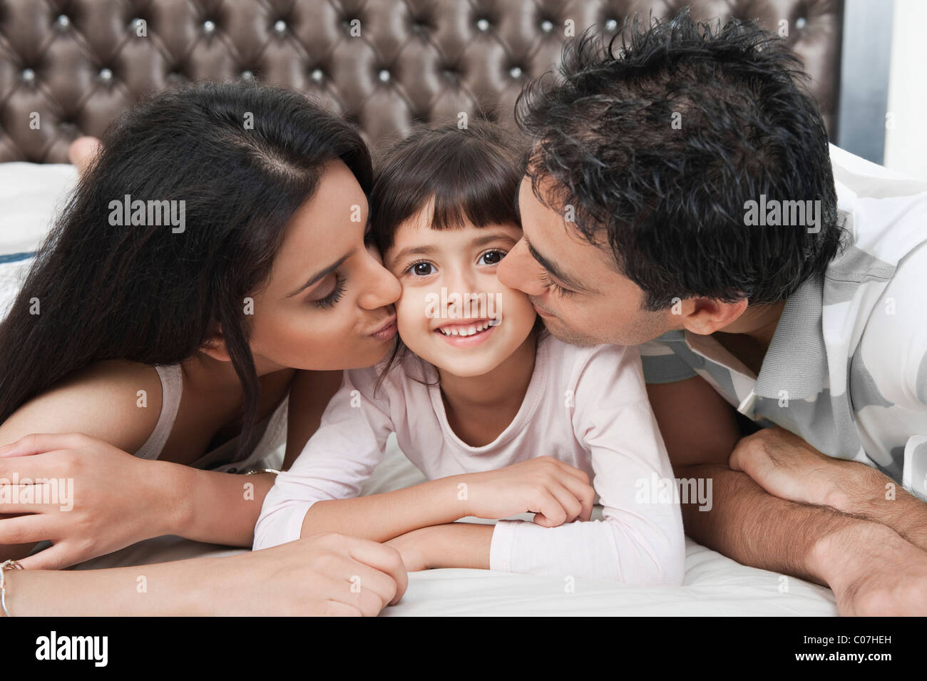 Parents kissing their daughter Stock Photo - Alamy