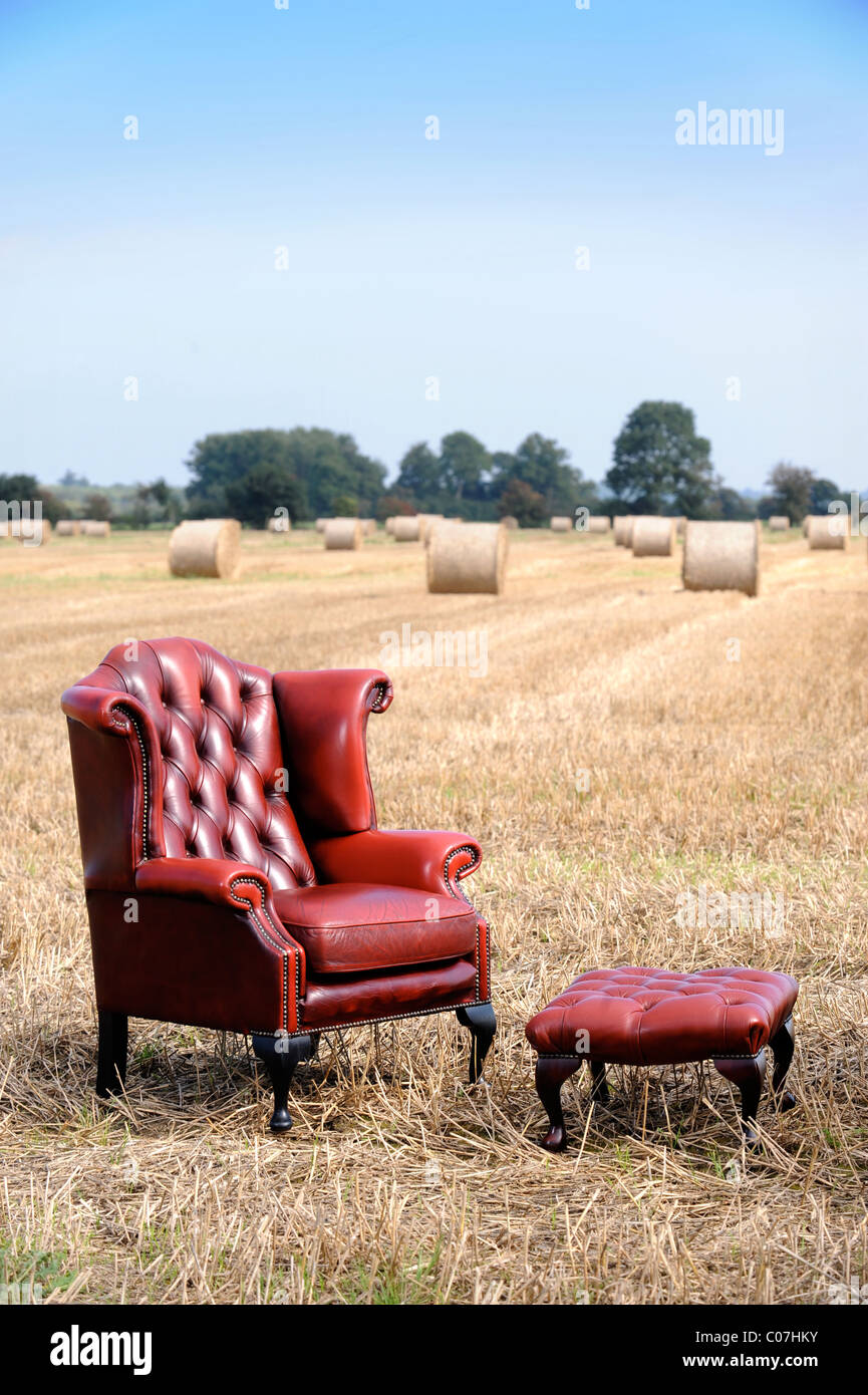 An antique red leather armchair in a field of harvested hay UK Stock ...
