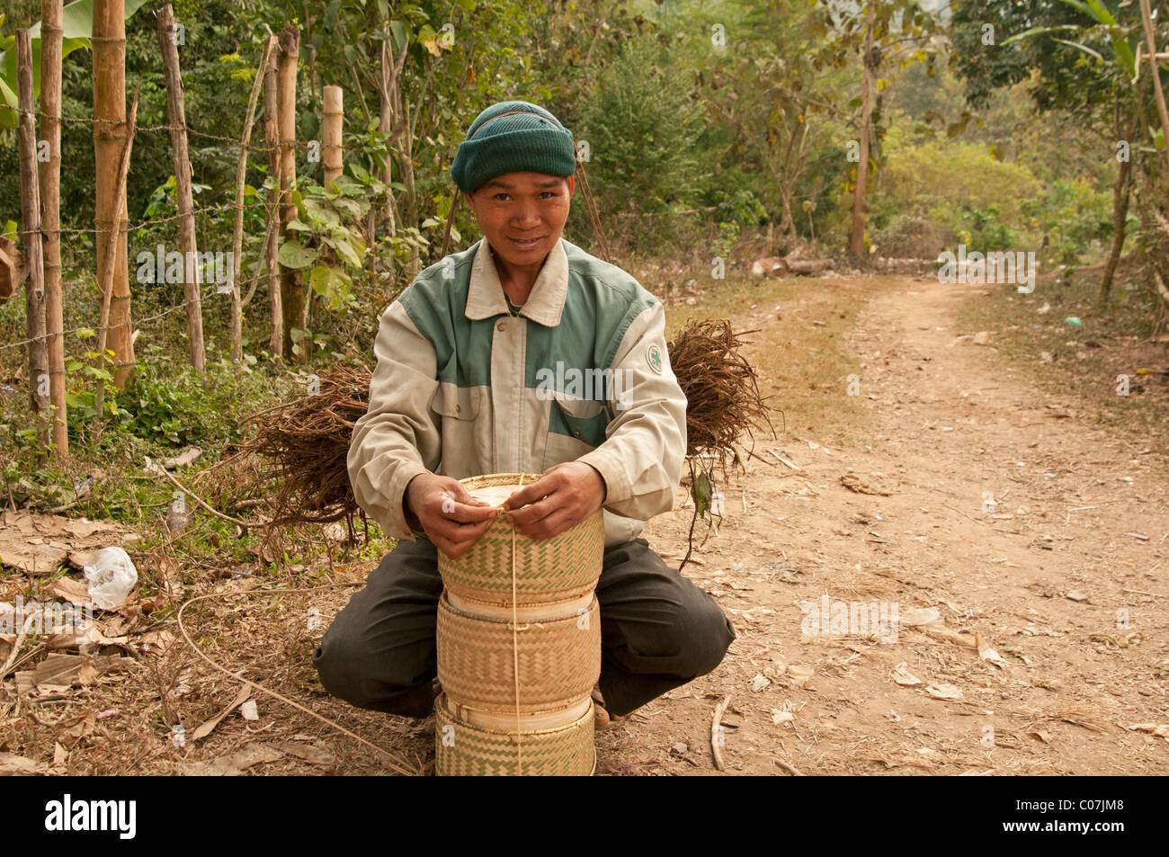 A Lao man with pack of forest roots on a jungle track in Northern Laos ...