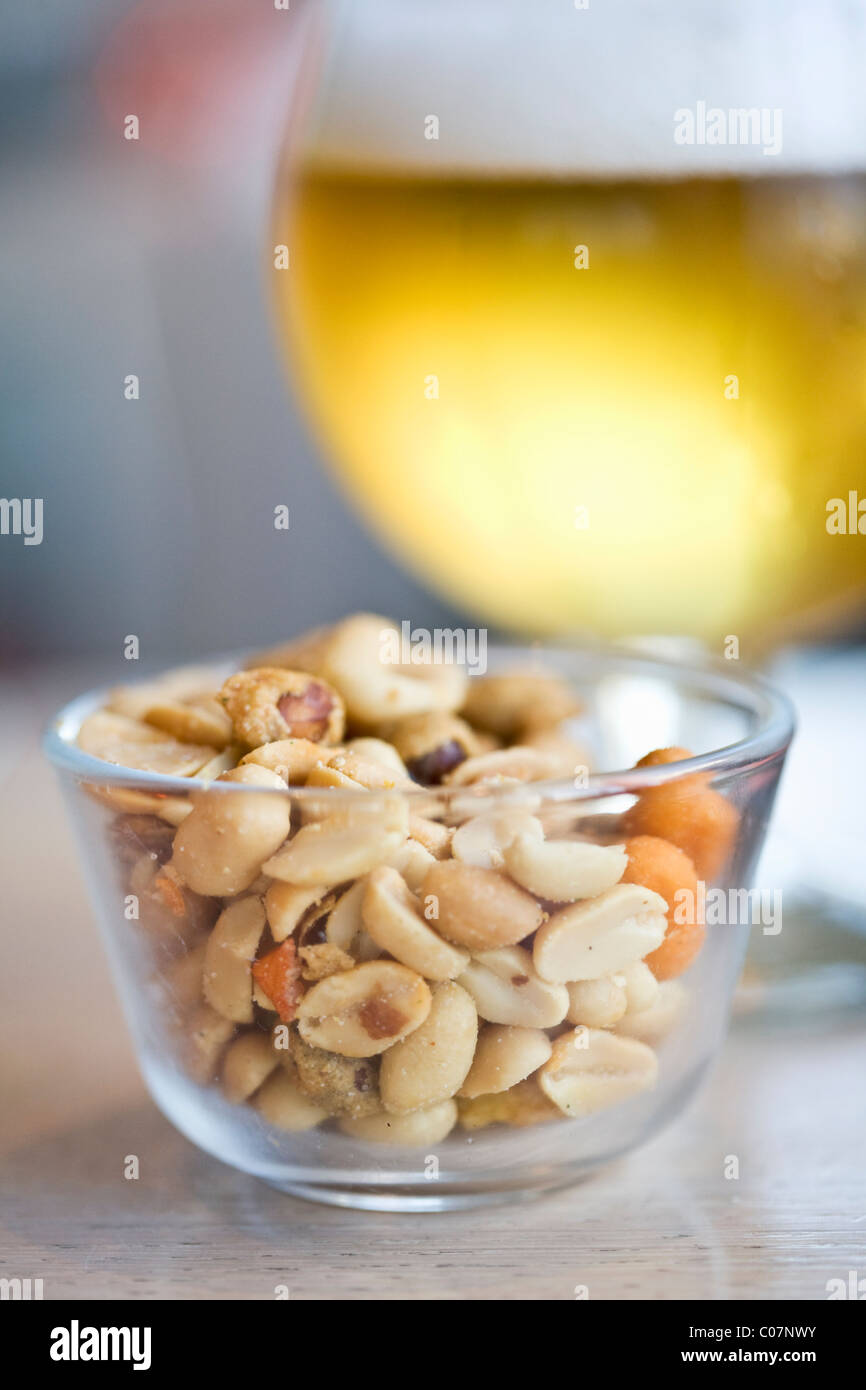 A bowl of nuts with a glass of beer Stock Photo - Alamy