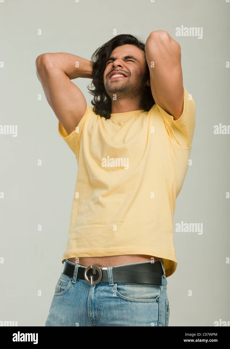 Man clenching teeth with his hands behind head Stock Photo - Alamy