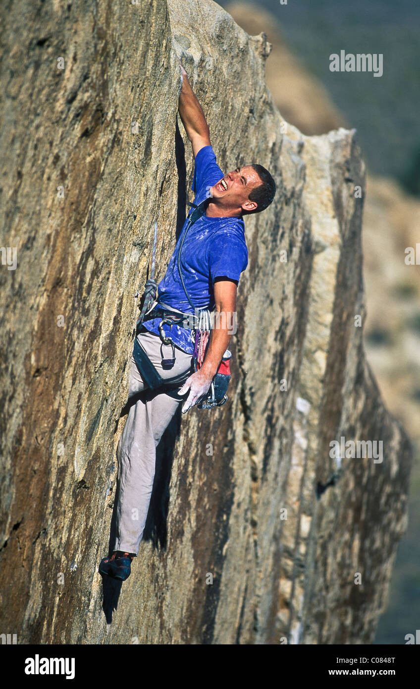 Rock climber struggles for his next grip on a overhanging cliff Stock ...