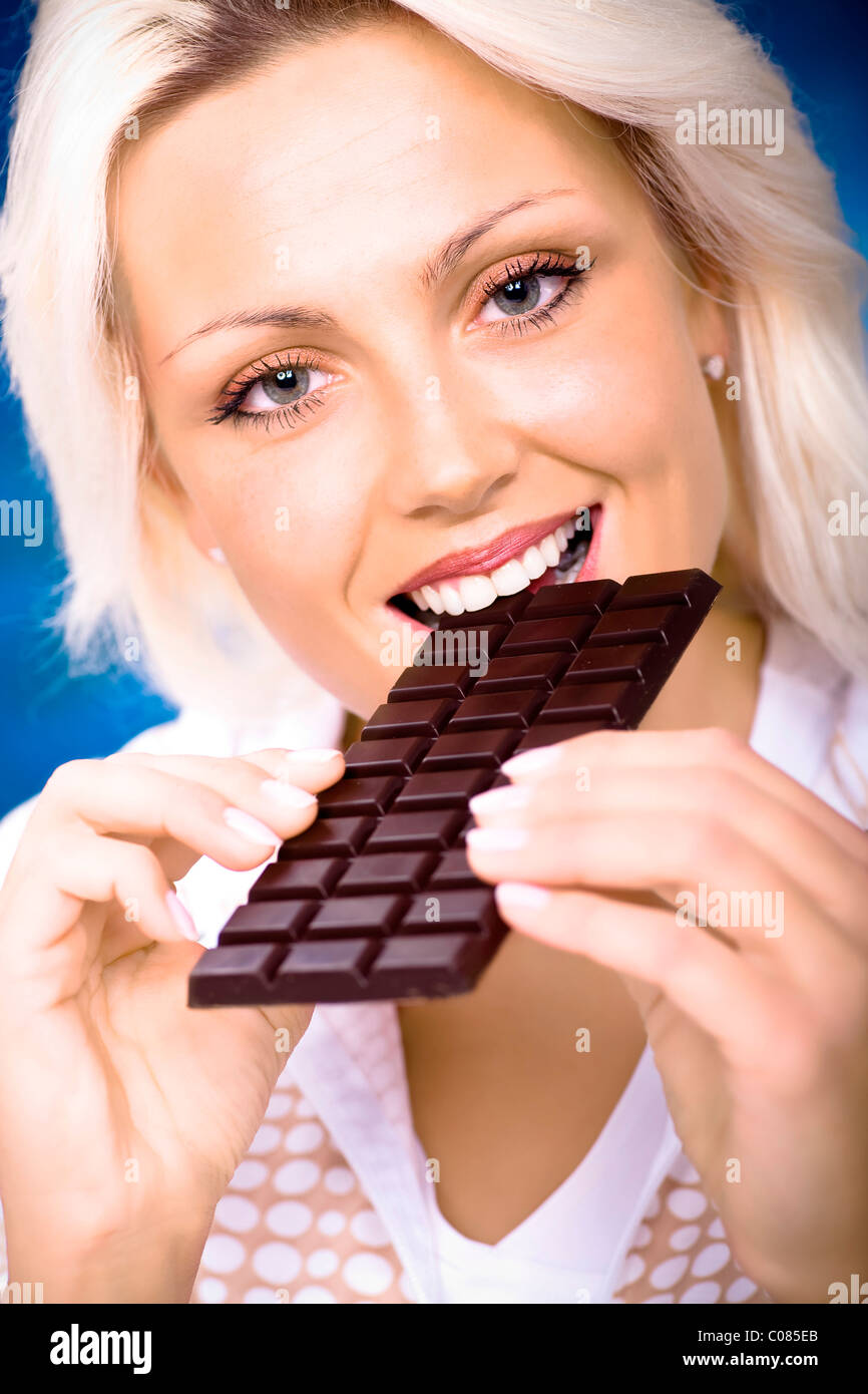 Young woman biting into a chocolate bar Stock Photo - Alamy
