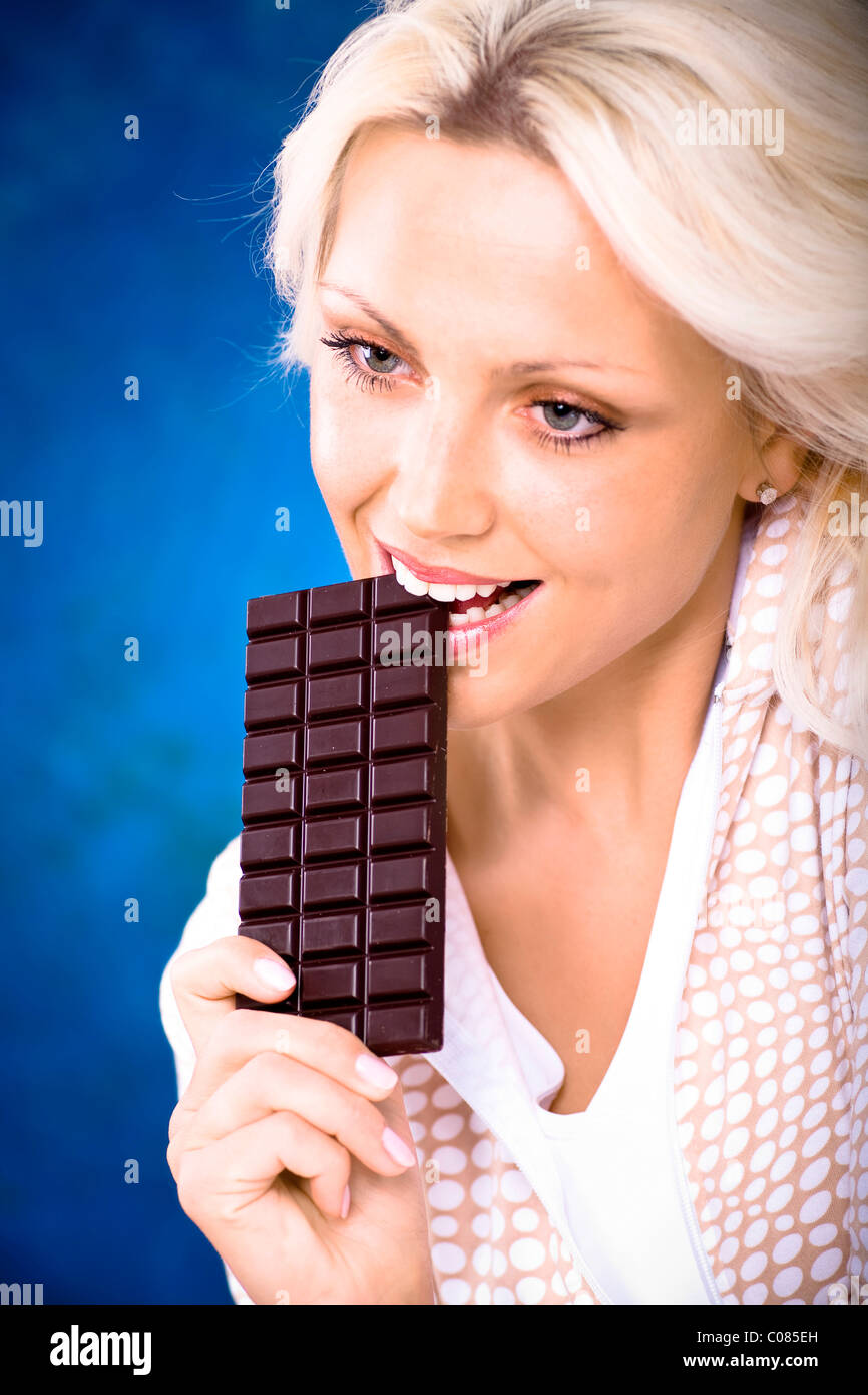Young woman biting into a chocolate bar Stock Photo - Alamy