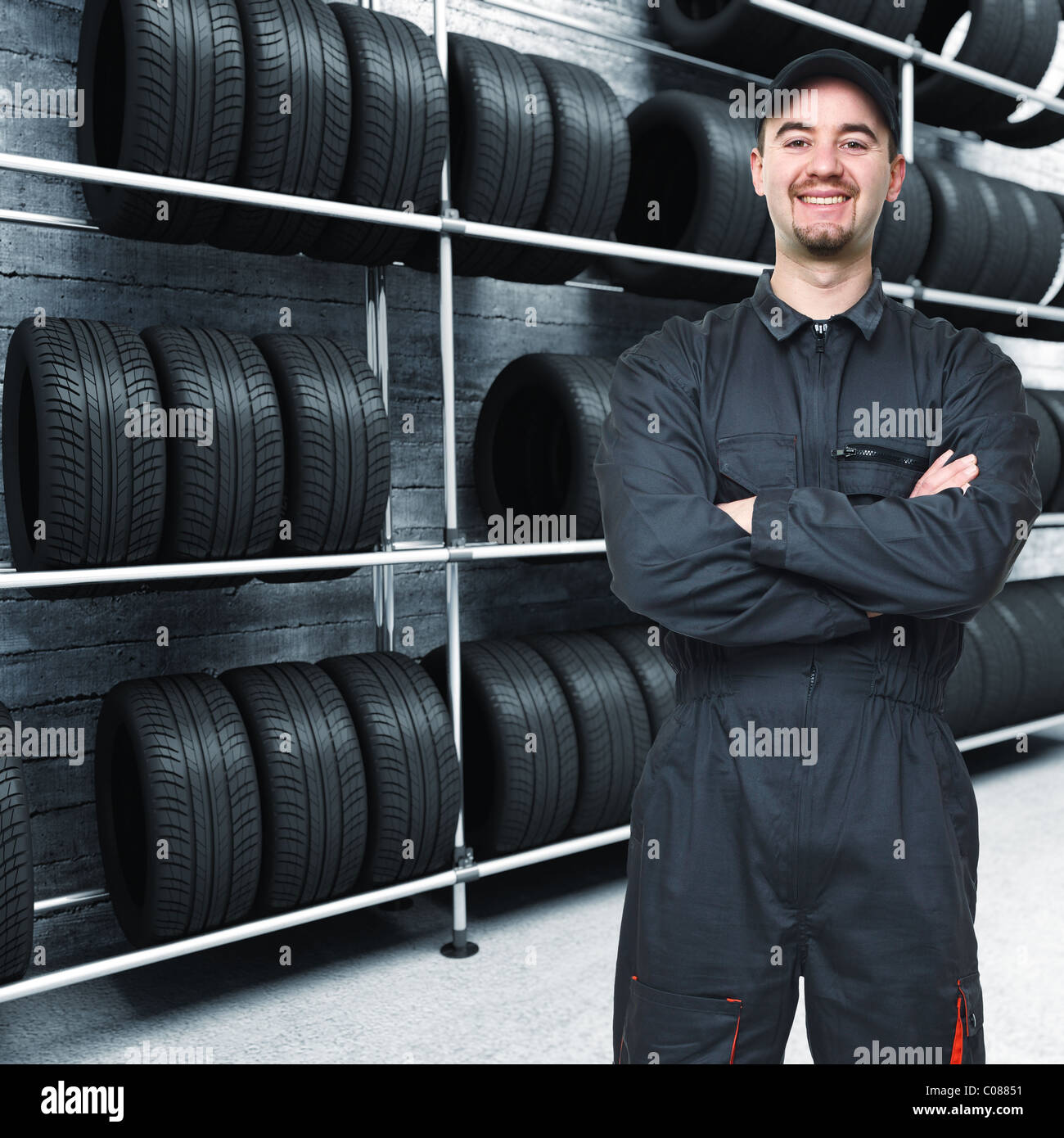 smiling mechanic and 3d tires garage background Stock Photo - Alamy