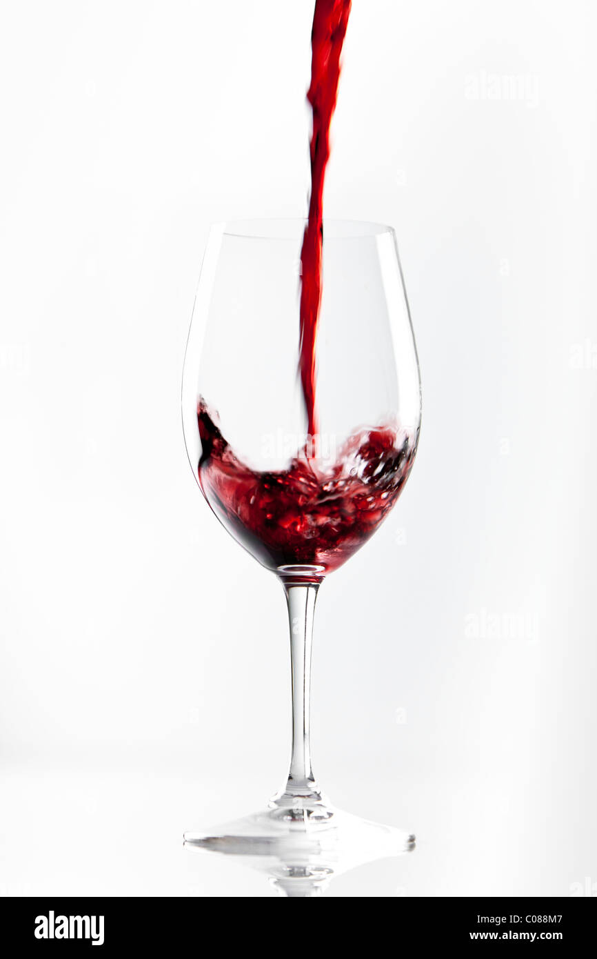 A glass of Red Wine being poured from the bottle on a white background ...