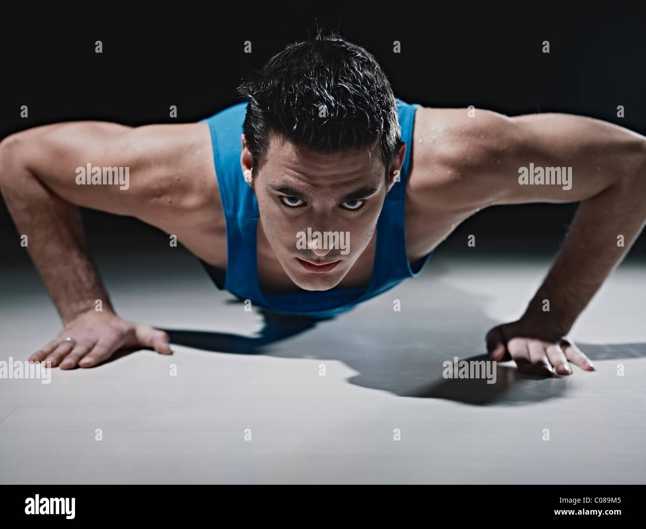 Young caucasian male in sportswear doing push ups on black background ...