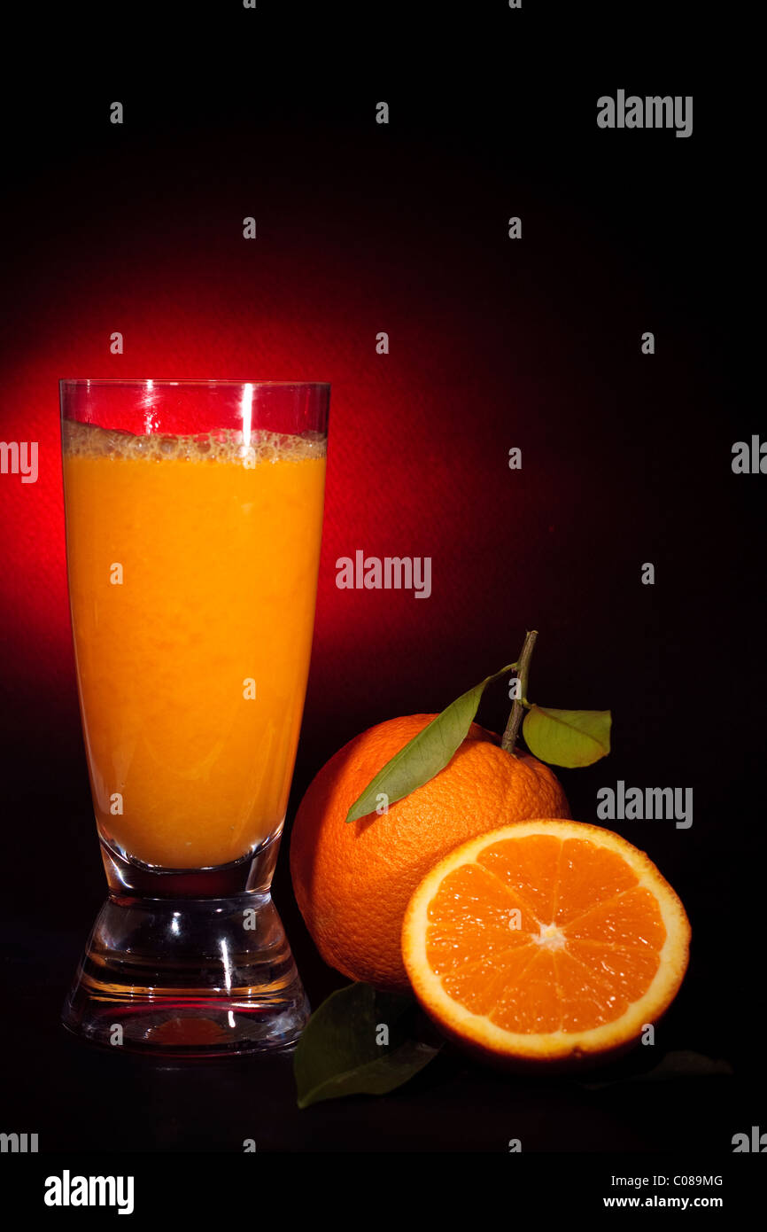 A glass of natural orange juice shooting on black background with red ...