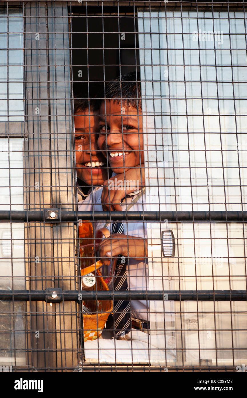 Happy smiling Indian boys in a school bus behind caged windows. Andhra ...