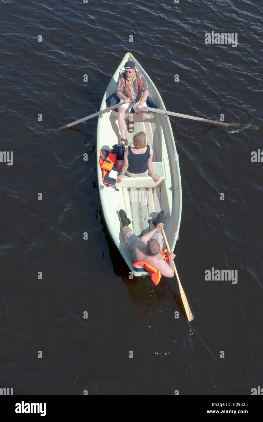 three people in rowing boat Stock Photo - Alamy