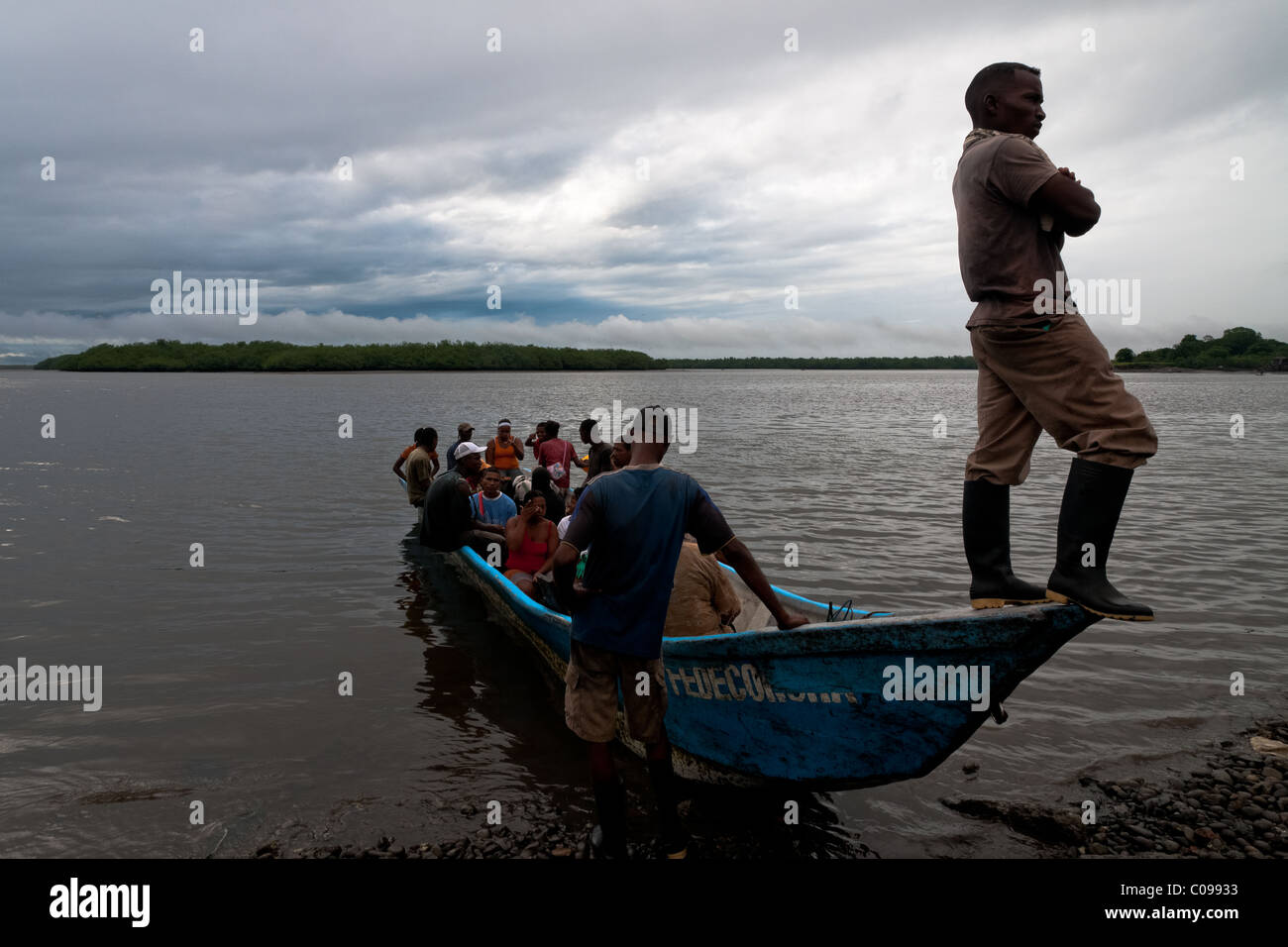 Colombian shellfish pickers embark on a canoe going to the mangrove ...